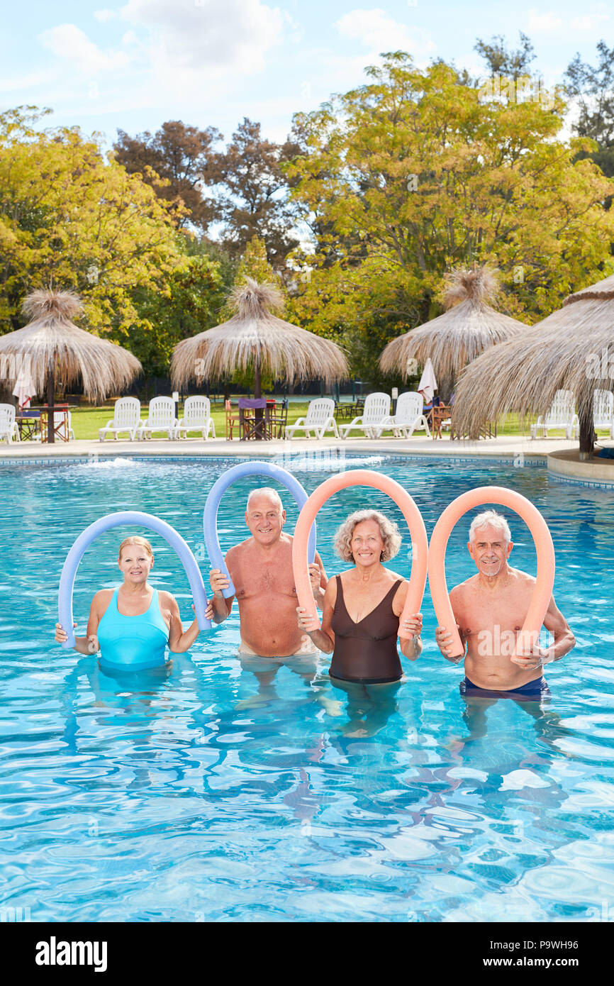 Group of seniors standing with swimming noodle in the swimming pool at ...