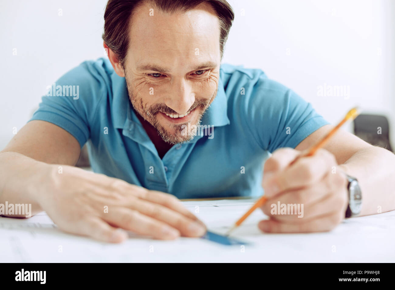 Easy work. Experienced young smiling engineer drawing the lines while ...