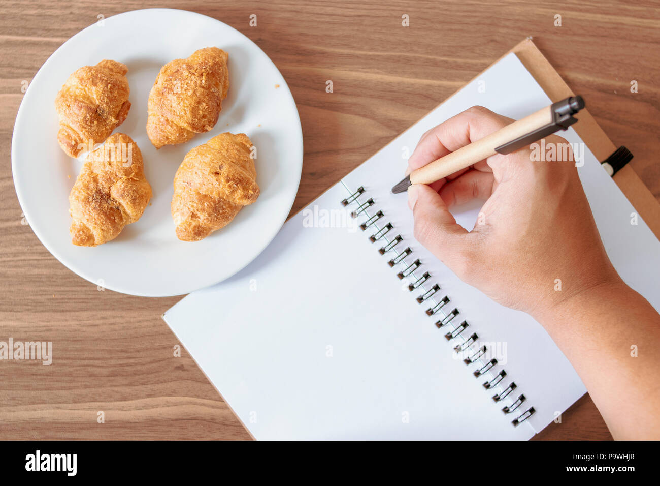 Taking notes at breakfast, along with some croissant Stock Photo - Alamy