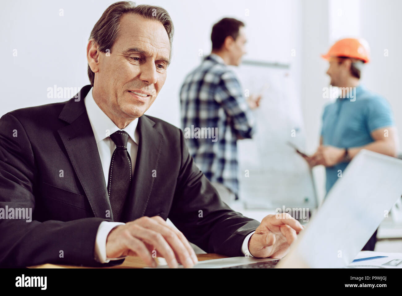 Progressive man. Elegant calm cheerful worker looking at the screen of ...