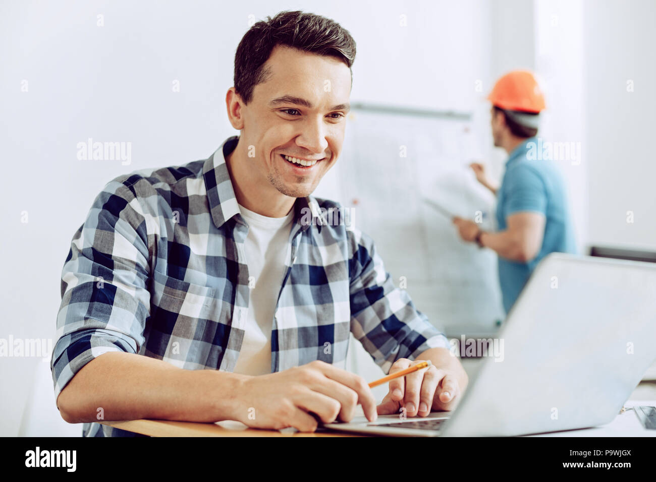 Happy employee. Smiling cheerful positive young worker looking at the ...
