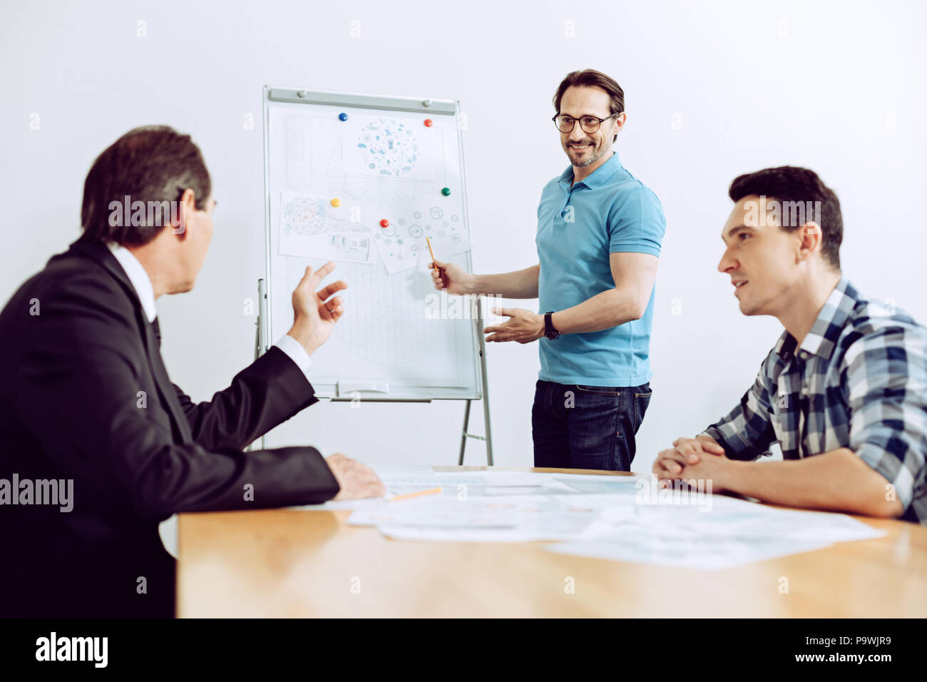 Clear information. Smiling calm positive worker explaining the diagram ...