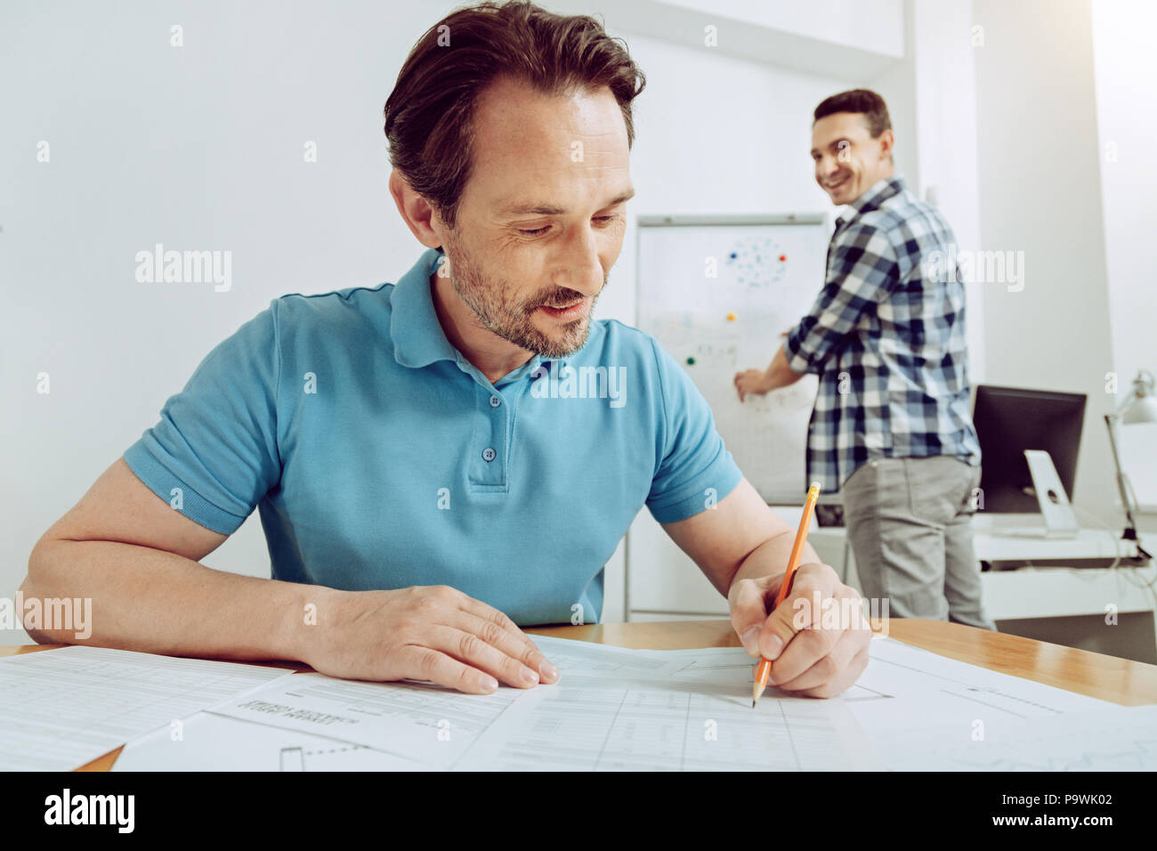 Calm engineer. Positive calm young engineer drawing a line while his ...