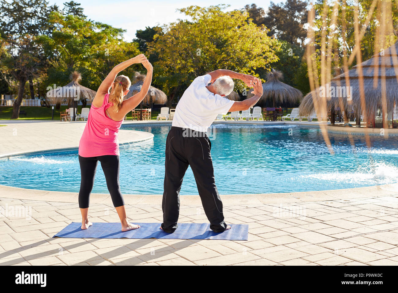 Senior couple at the pool doing a stretching exercise on a spa vacation ...