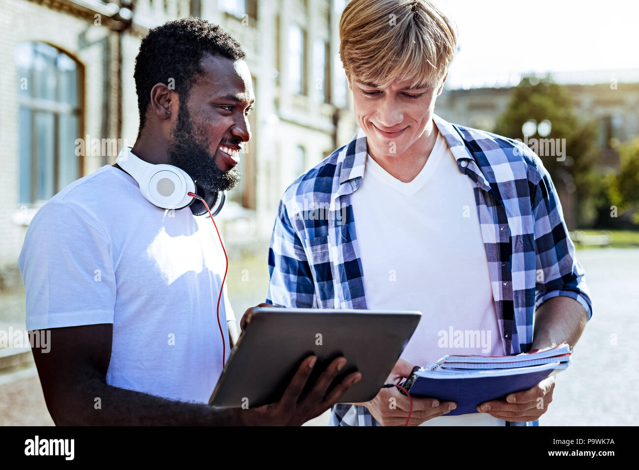 Sunny day. Kind boys keeping smile on faces and standing next to each ...