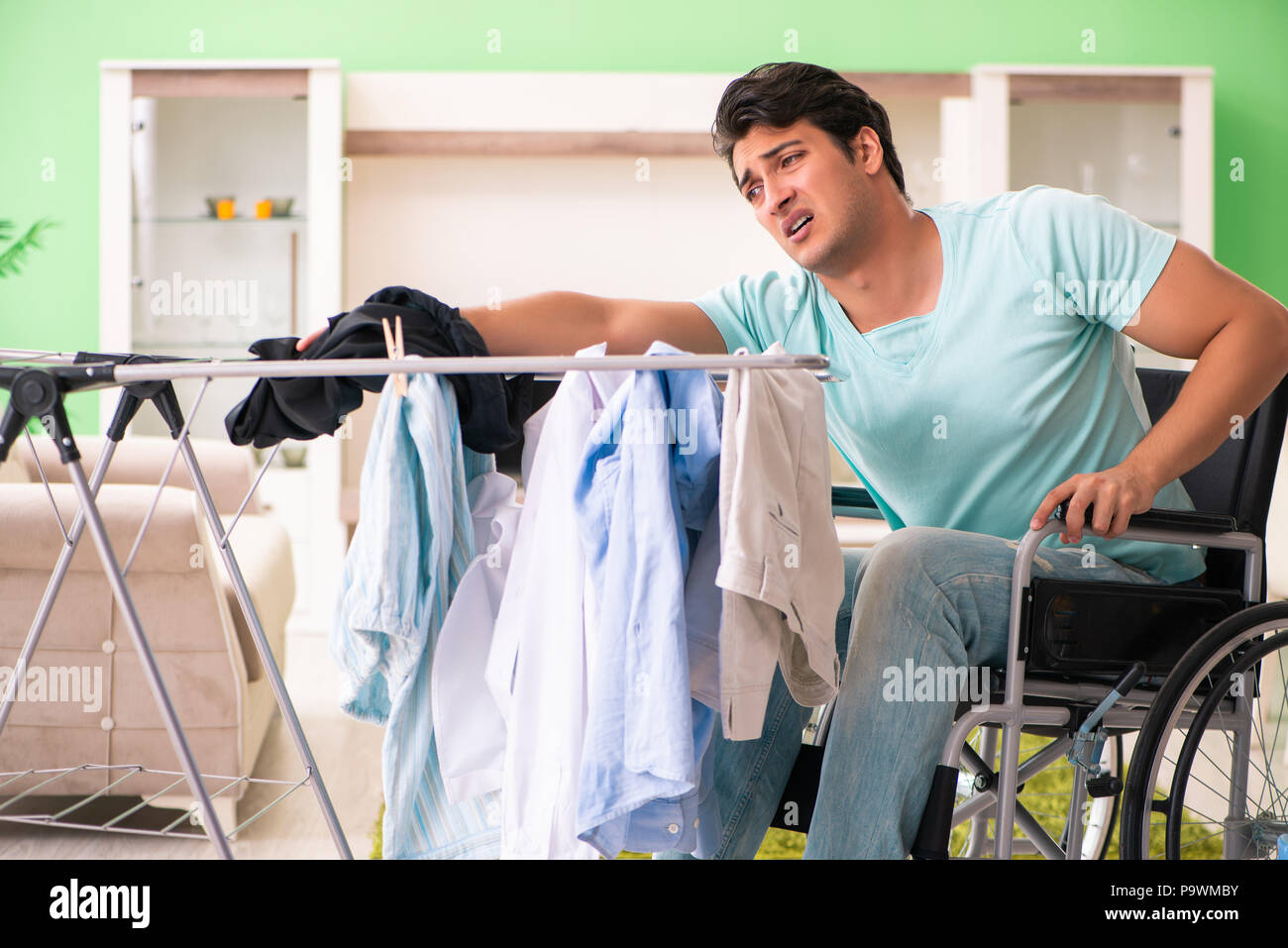 Disabled man on wheelchair doing laundry Stock Photo - Alamy