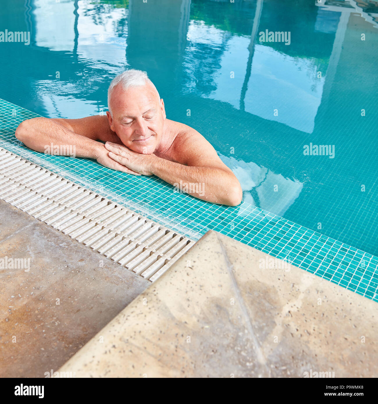 Exhausted senior man in the swimming pool relaxes at the pool edge ...