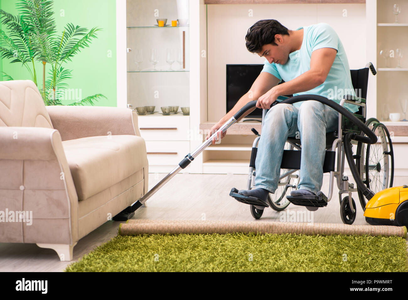 Disabled man on wheelchair vacuum cleaning house Stock Photo - Alamy
