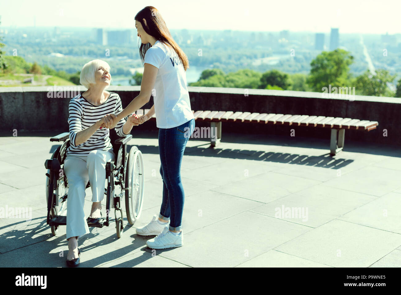 Joyful young female helping old lady Stock Photo - Alamy