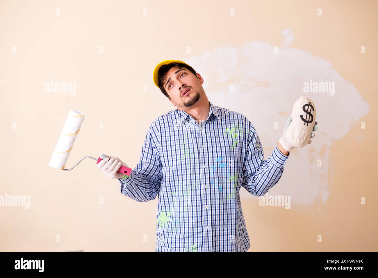 Painter man painting the wall at home Stock Photo - Alamy