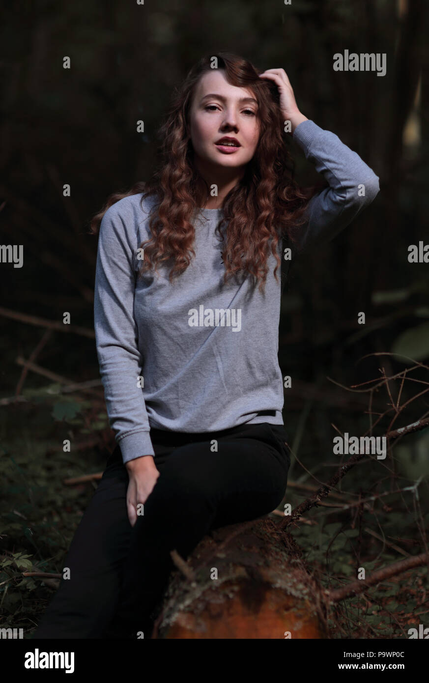 beautiful young woman sitting on a log Stock Photo - Alamy