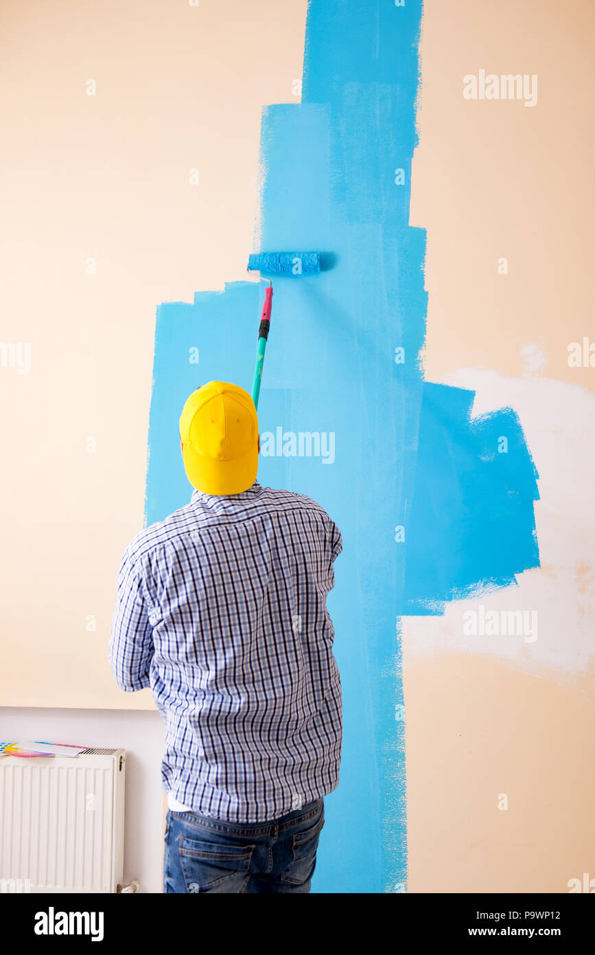 Painter man painting the wall at home Stock Photo - Alamy