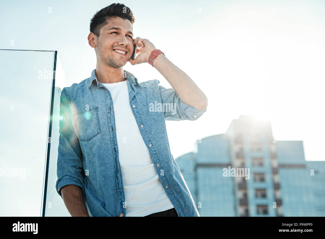 Confident male person leaning on glass wall Stock Photo - Alamy