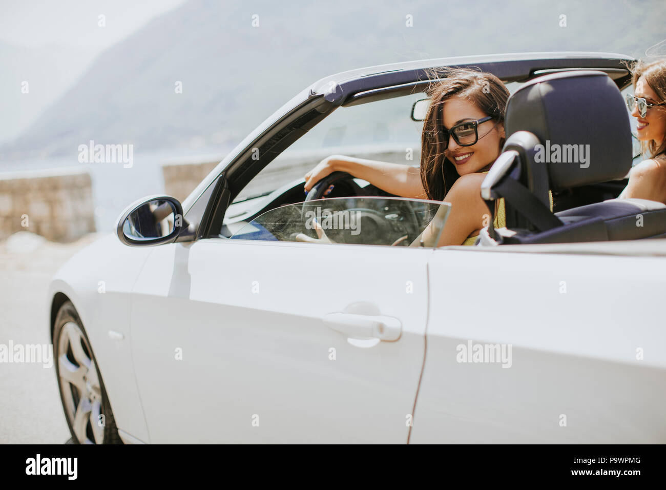 Young woman with sunglasses driving her convertible top automobile on ...