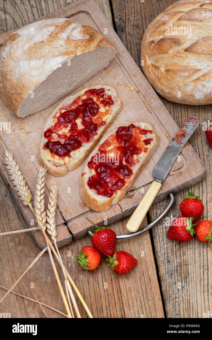 Strawberry jam on bread with wheat and strawberries on a wood ...
