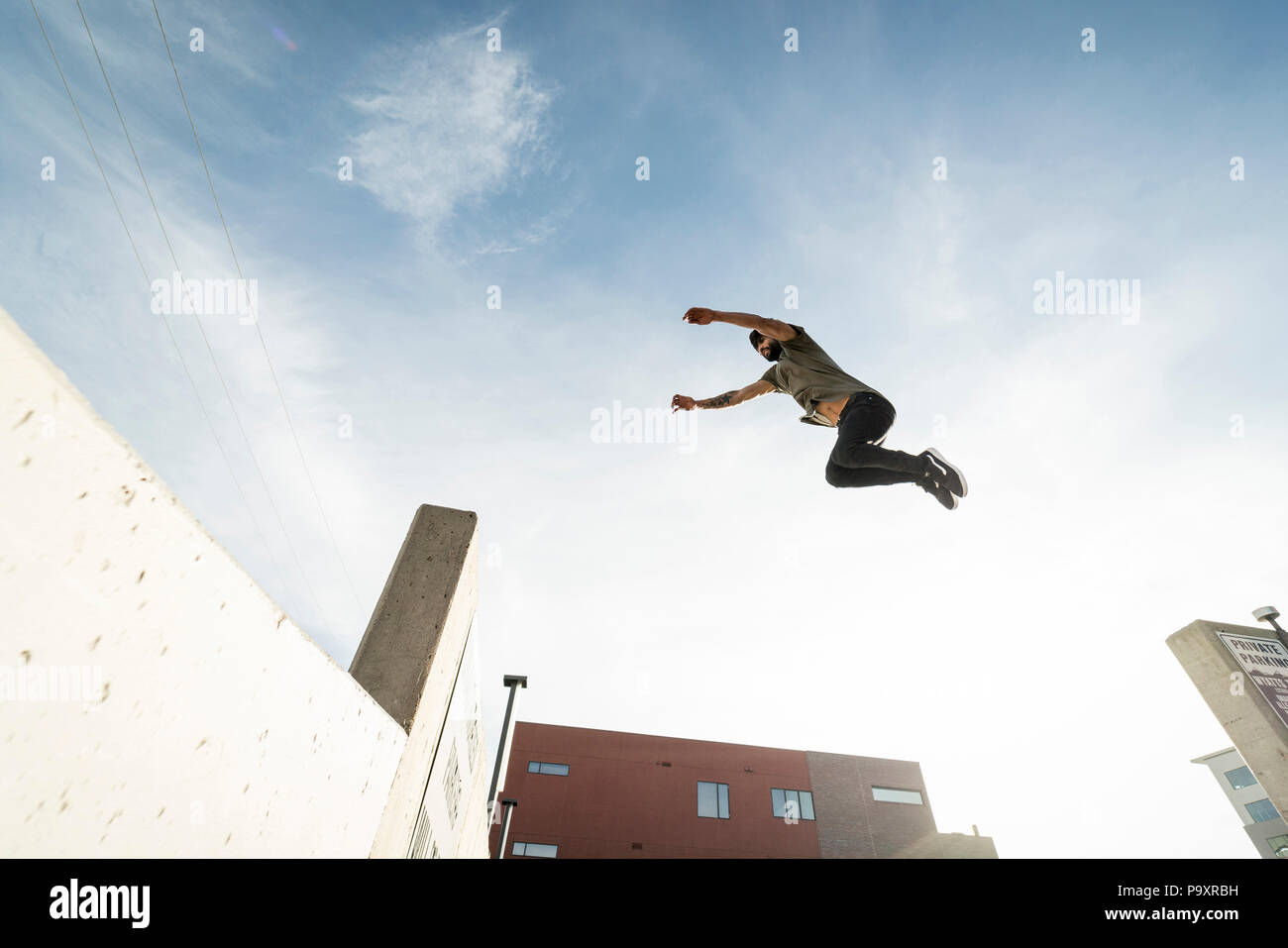 Side view of single male parkour athlete jumping from one wall to ...