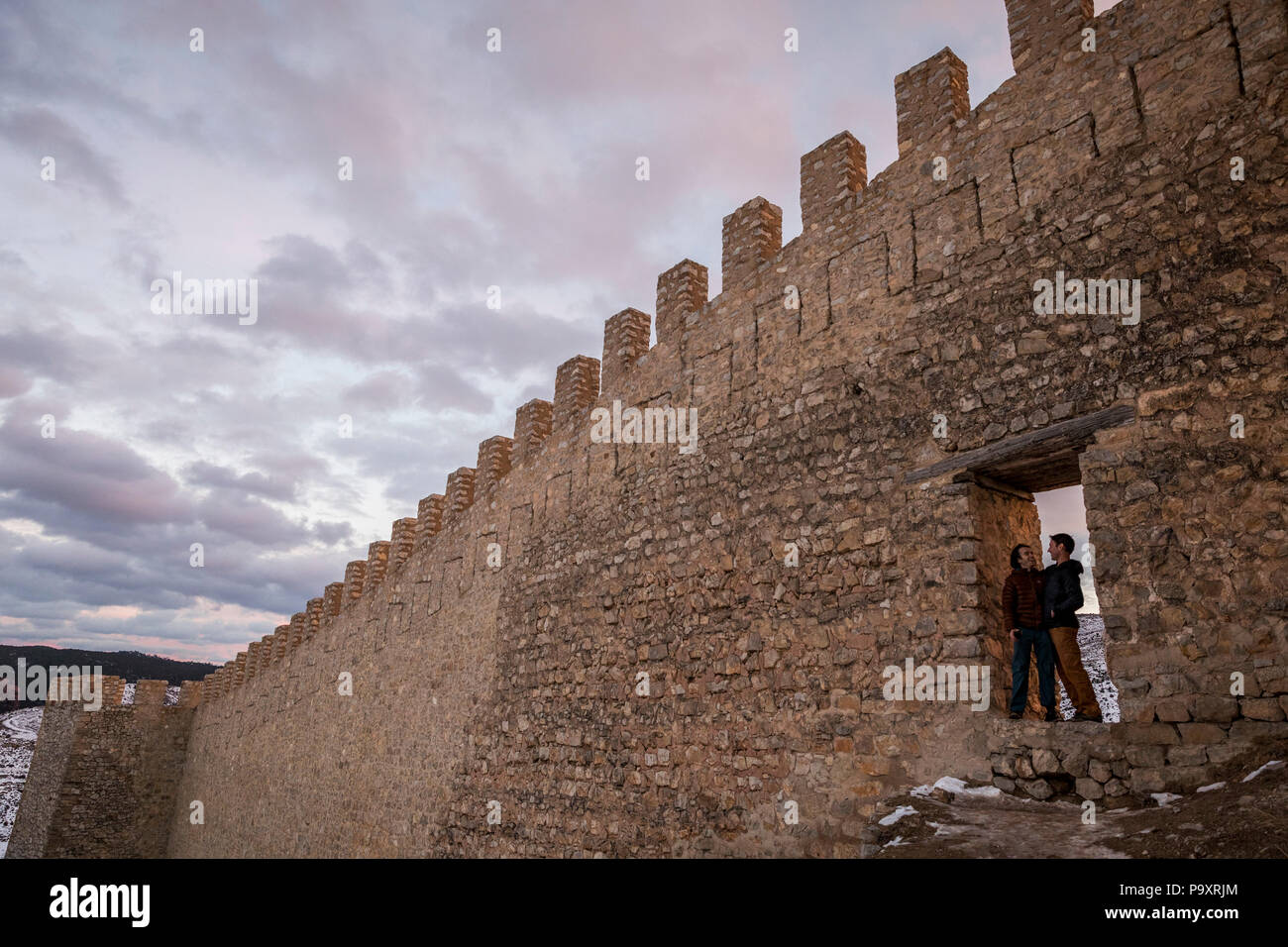 Two people posing inside opening of castle wall, Albarracin, Zaragoza ...