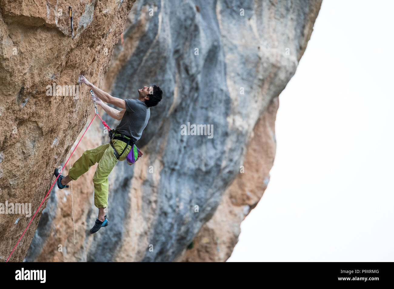 Side view of single adventurous man rock climbing up cliff, Siurana ...