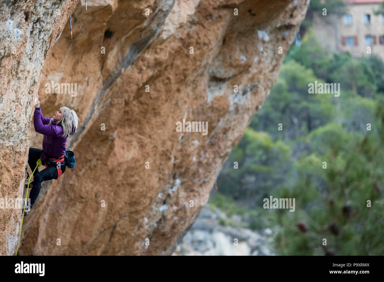 Side view of single adventurous woman rock climbing up cliff, Siurana ...