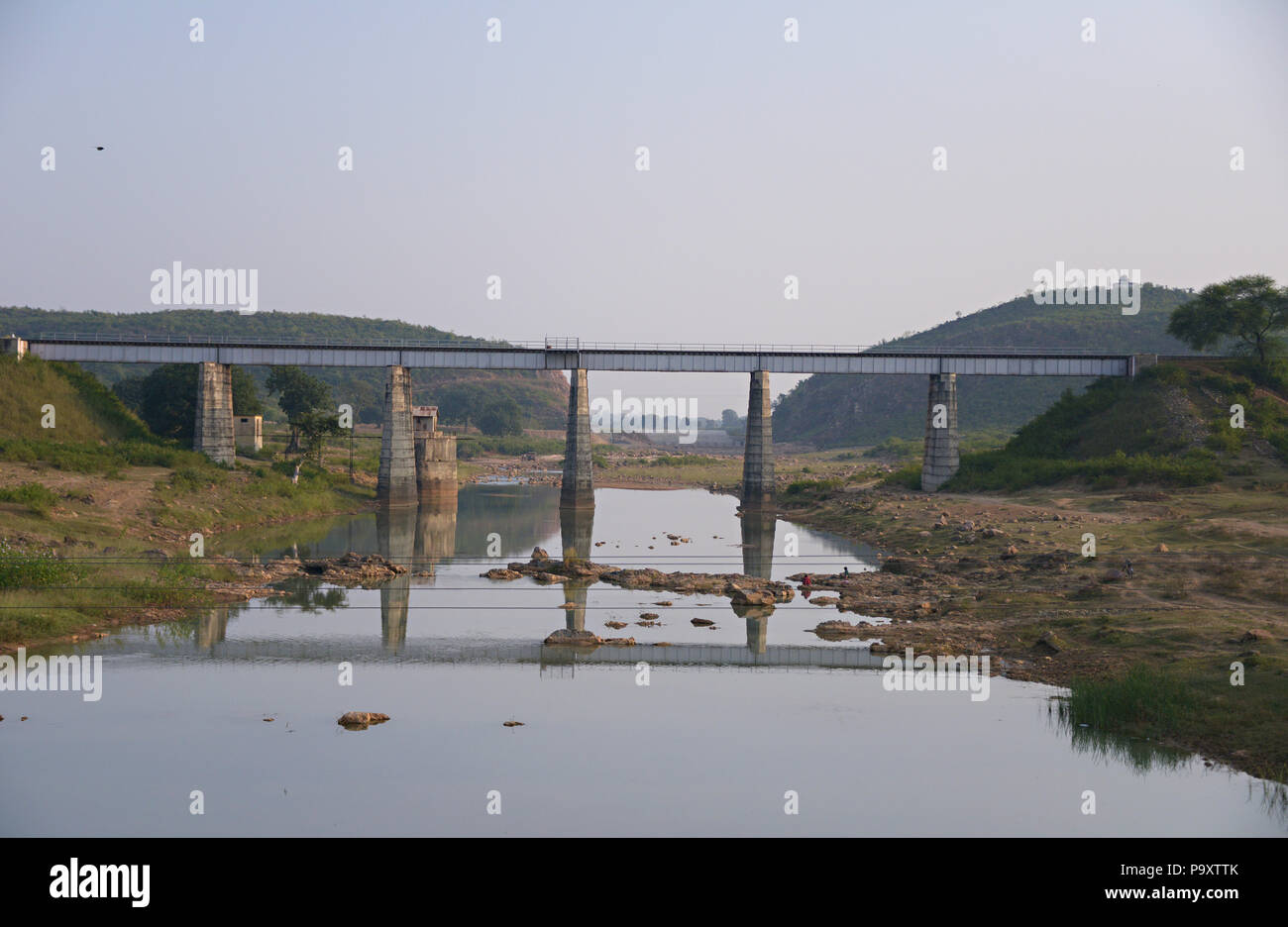 Landscape view of a narrow bridge stretching across a river creating a ...