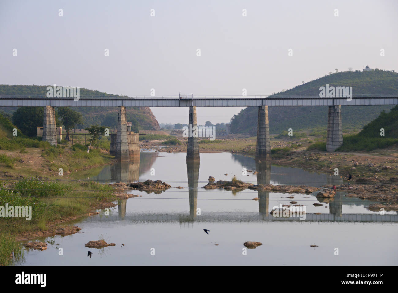 Landscape view of a narrow bridge stretching across a river creating a ...