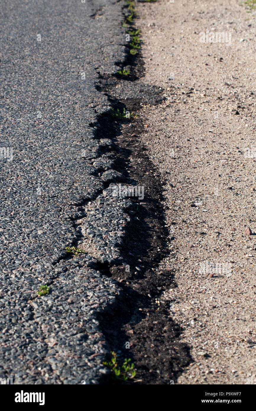 edge with cracks and other details of an asphalt road and roadside from ...