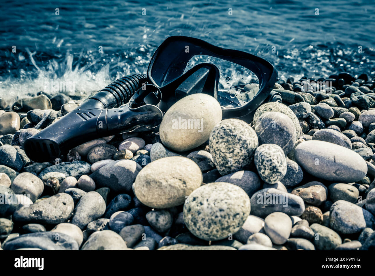 The black rubber driver's mask and the snorkel lie on the seashore at ...