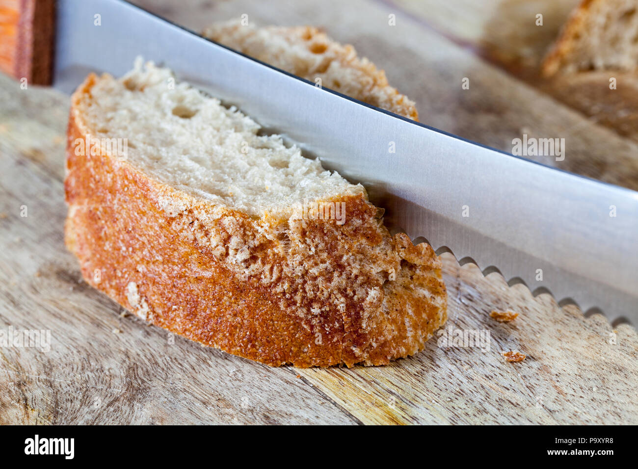 a fresh loaf of bread, which is cut with a sharp knife into pieces on a ...