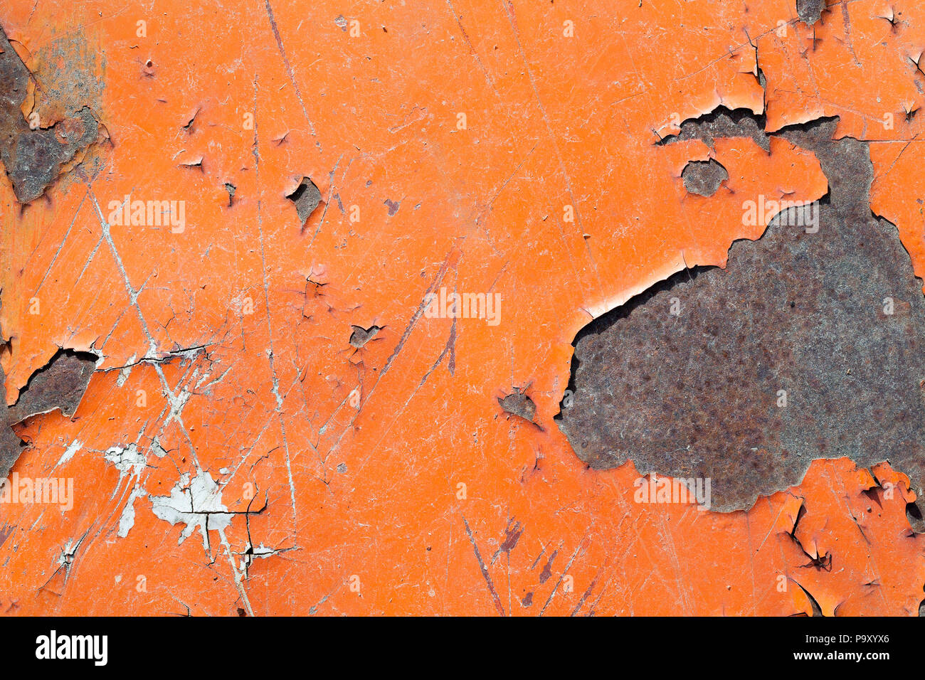 old rusting metal surface, painted with orange paint, which is peeling ...