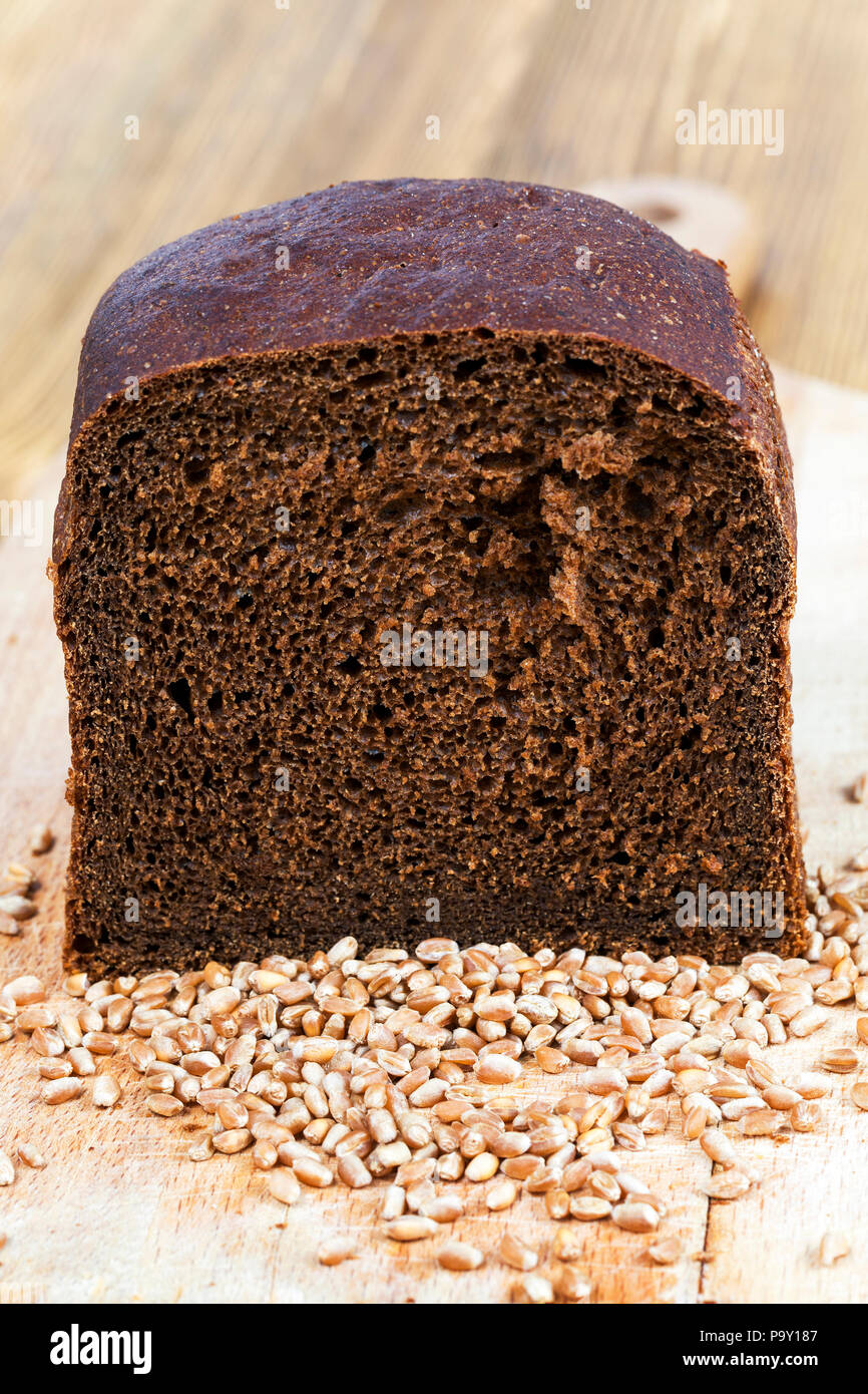 half a black loaf of rye bread lying on a thin white pita bread with ...