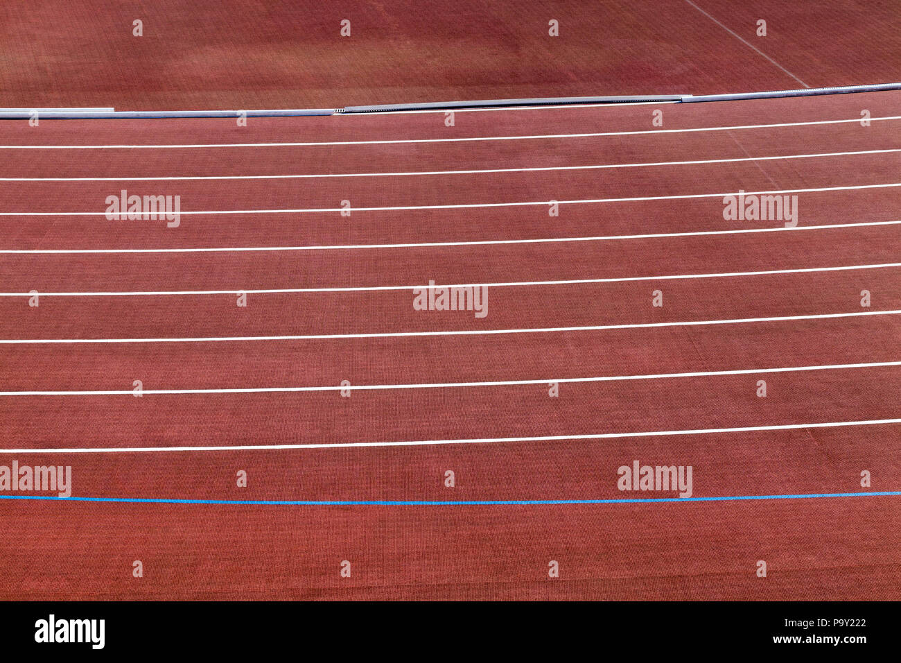 red treadmill in a large stadium, separated by white stripes at the ...