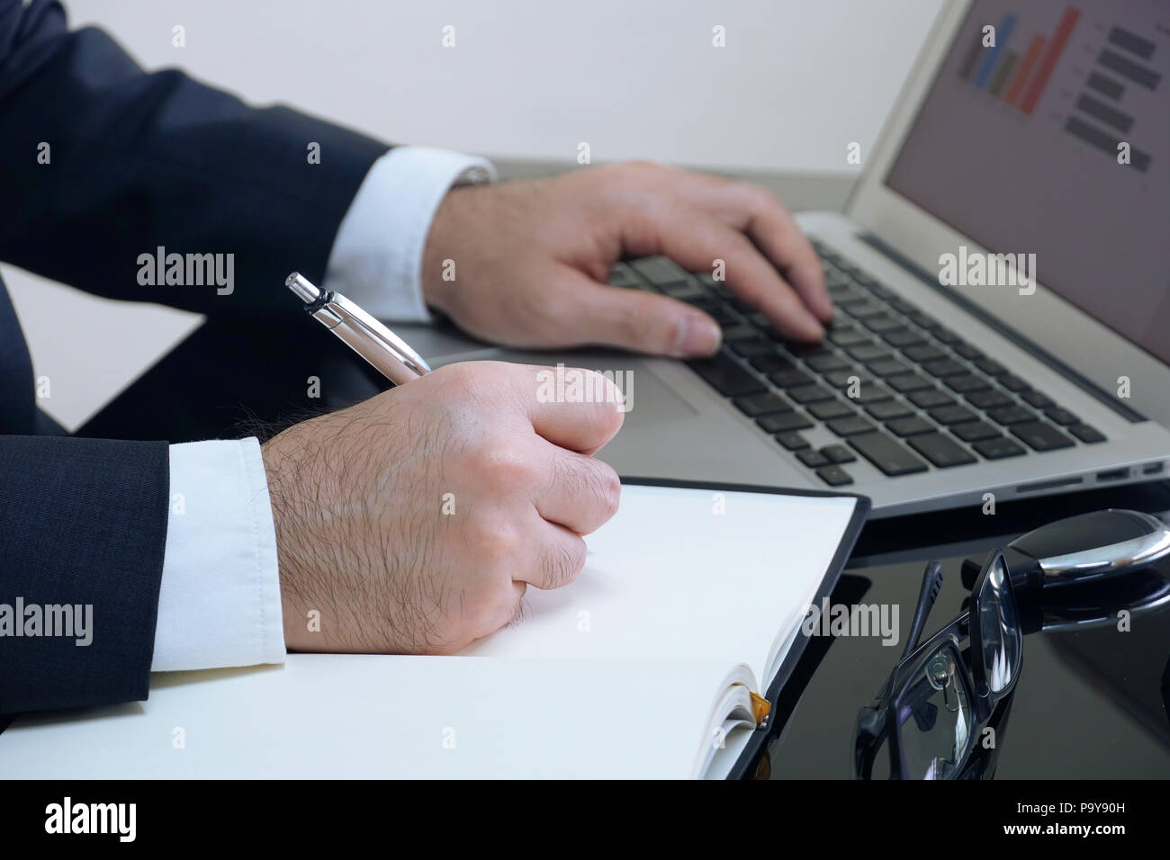 Business man check data from notebook and wtite down data on organizer ...