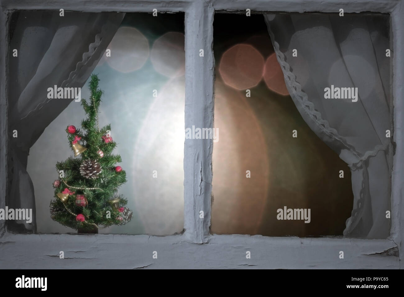 Humble christmas window seeing ornated tree against flare background ...