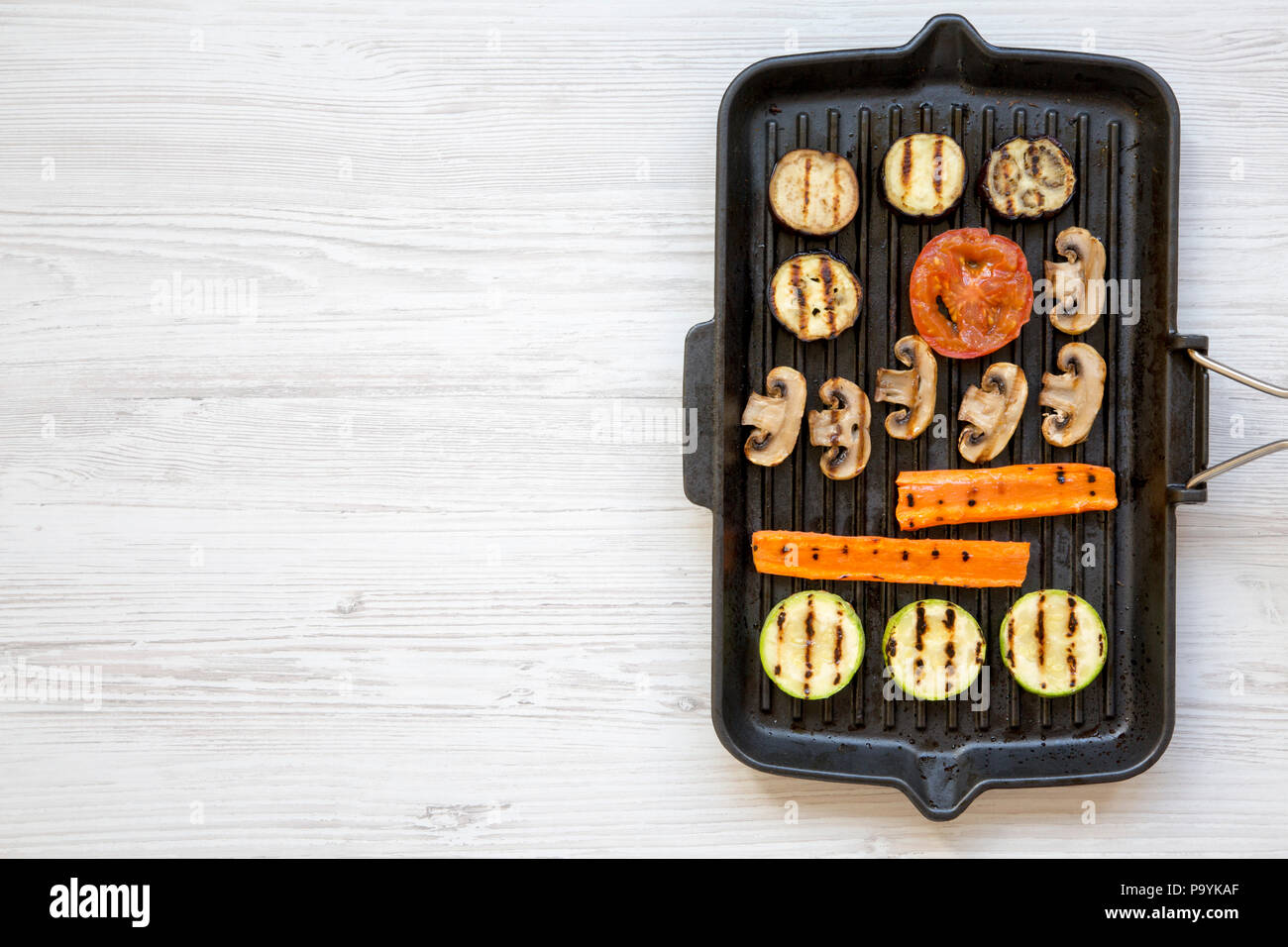 Top view, grilled vegetables in a grilling pan on a white wooden table ...