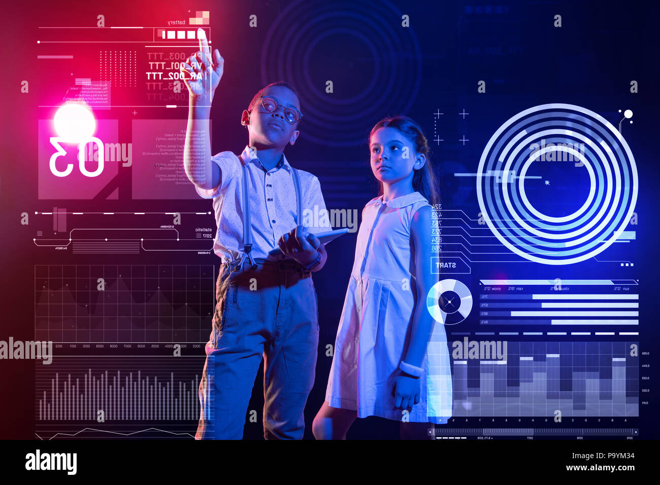 Confident boy pointing the screen while showing his friend how to use a ...