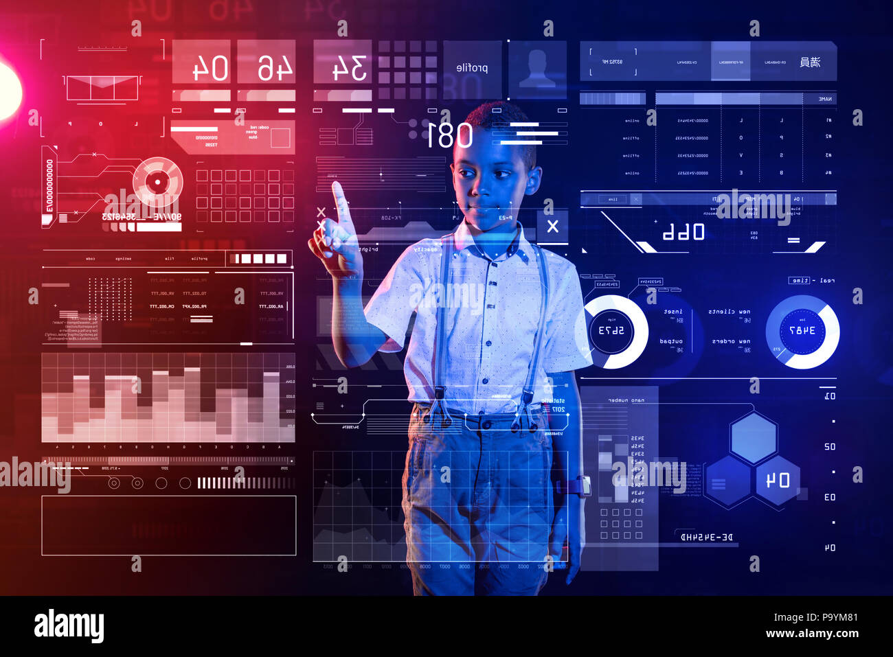 Calm boy carefully touching the screen while using a futuristic gadget ...