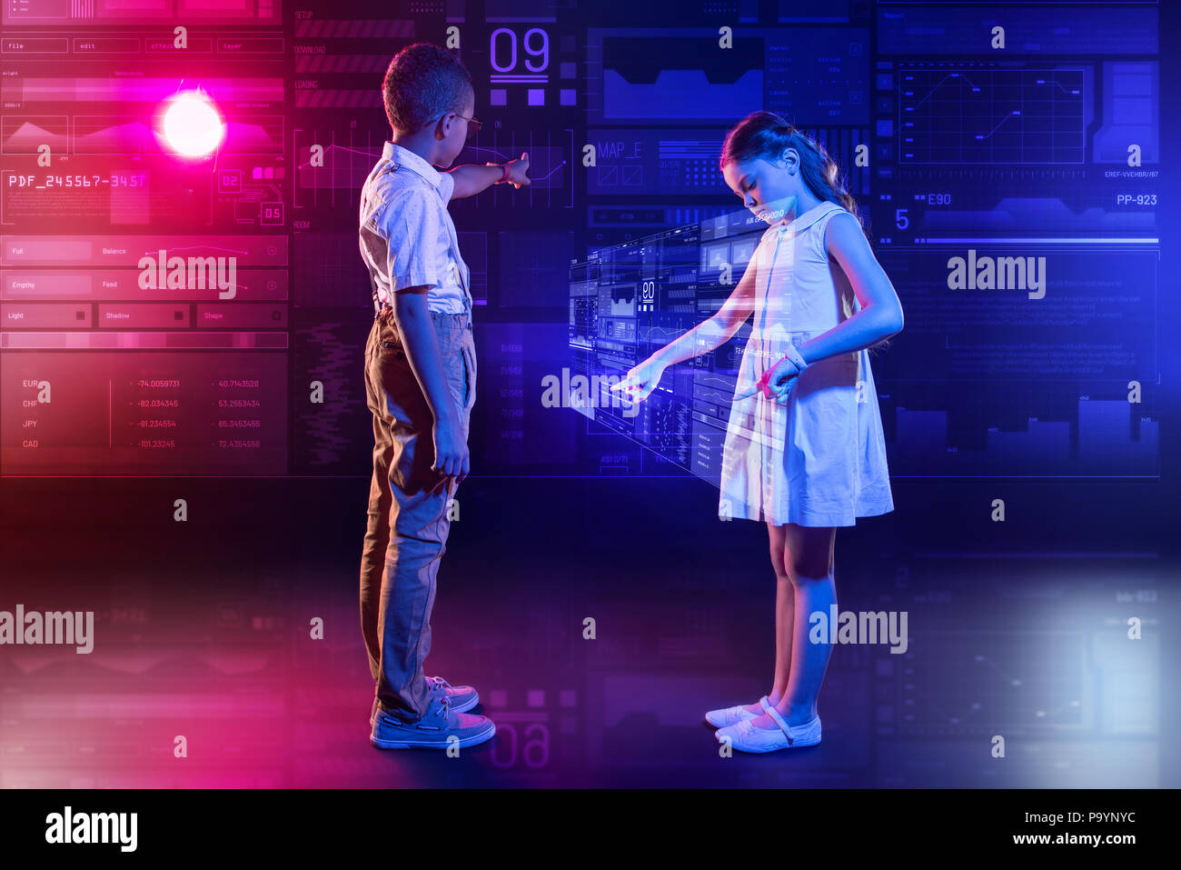 Calm boy touching the screen while a girl working with holograms Stock ...