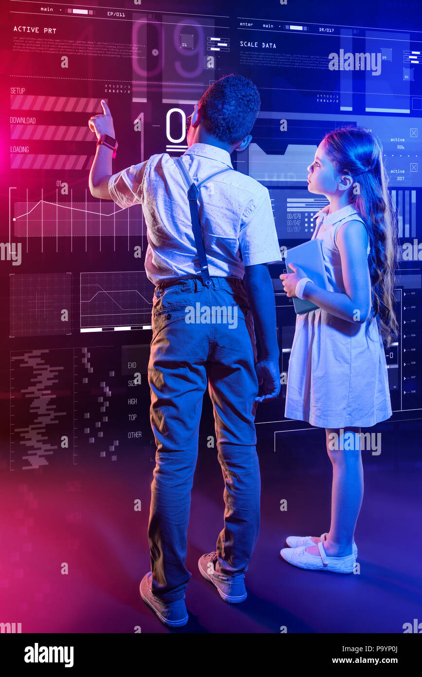 Diligent girl looking at the screen while her classmate pointing at it ...