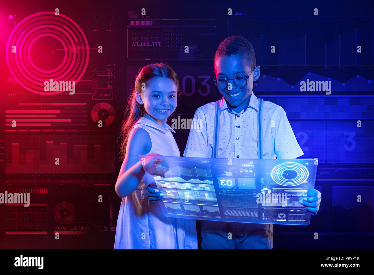 Happy kids looking at the bright screen and smiling Stock Photo - Alamy