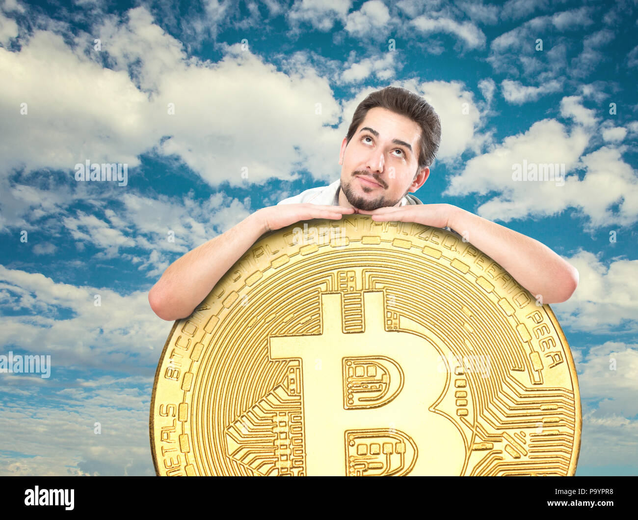 A happy man with a huge bitcoin coin on a beautiful sky with clouds ...