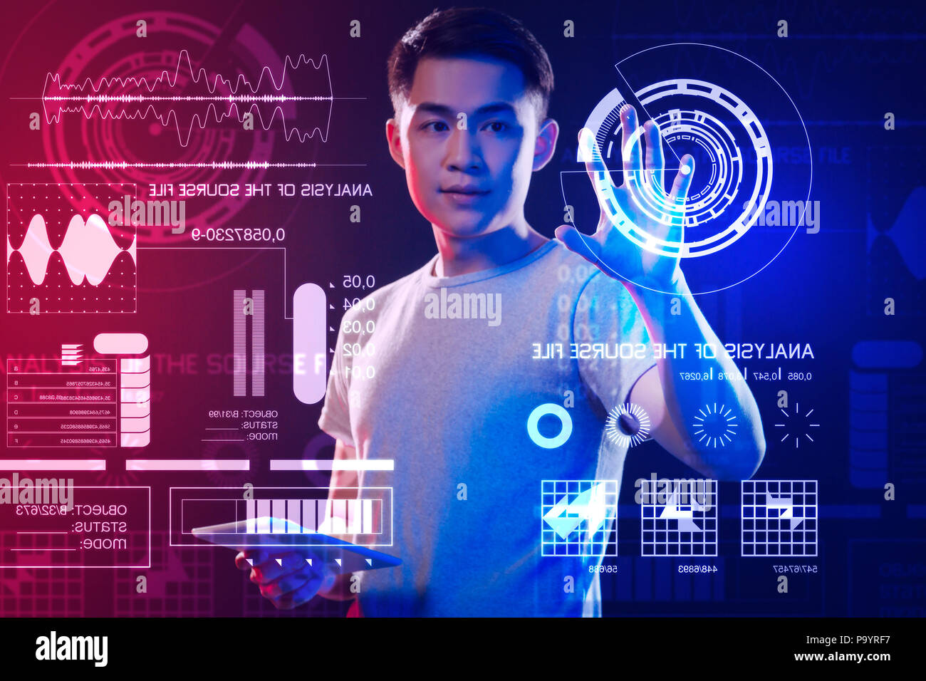 Calm young man carefully touching the screen while standing with a ...