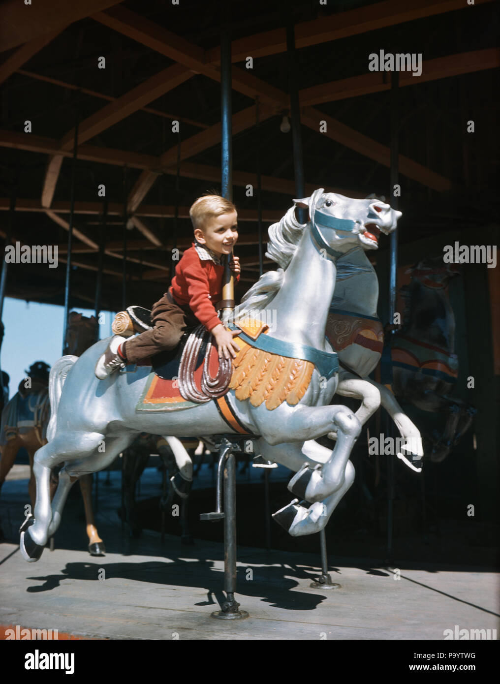 1950s HAPPY SMILING LITTLE BOY RIDING GALLOPING CAROUSEL HORSE ON MERRY ...