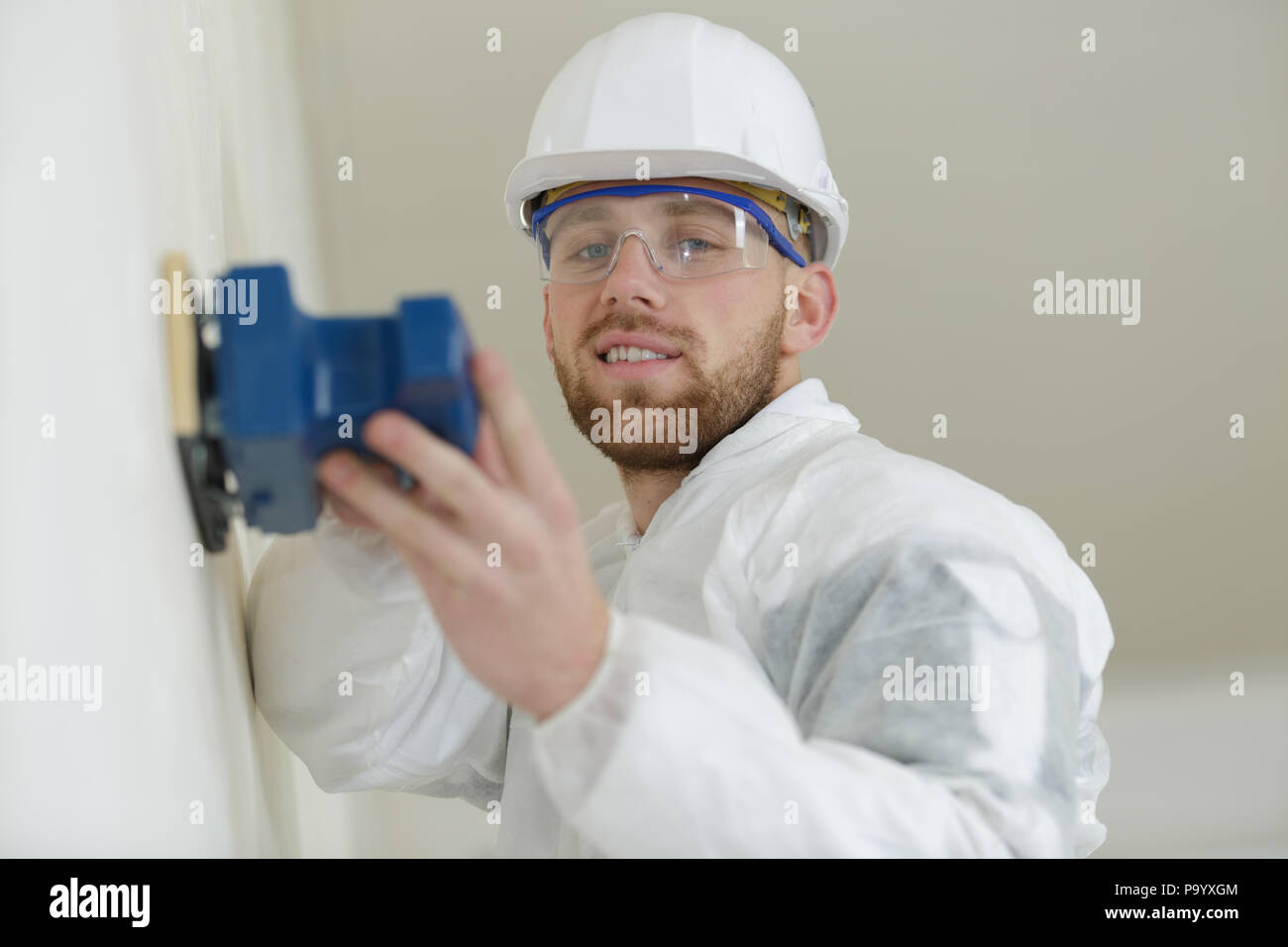 happy young contractor sanding the wall Stock Photo - Alamy