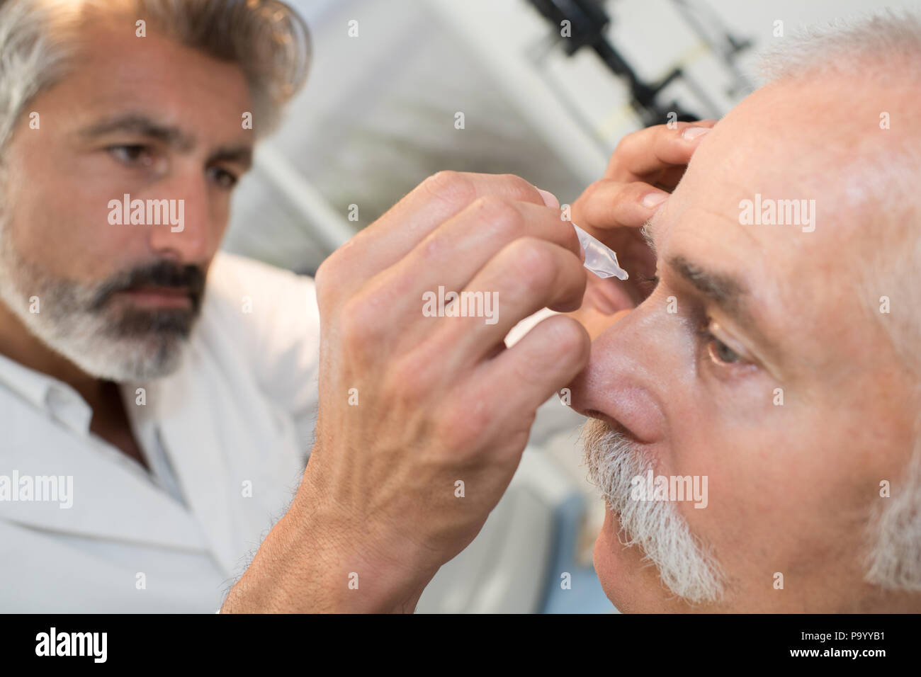 doctor dripping eye drops to senior patient Stock Photo - Alamy