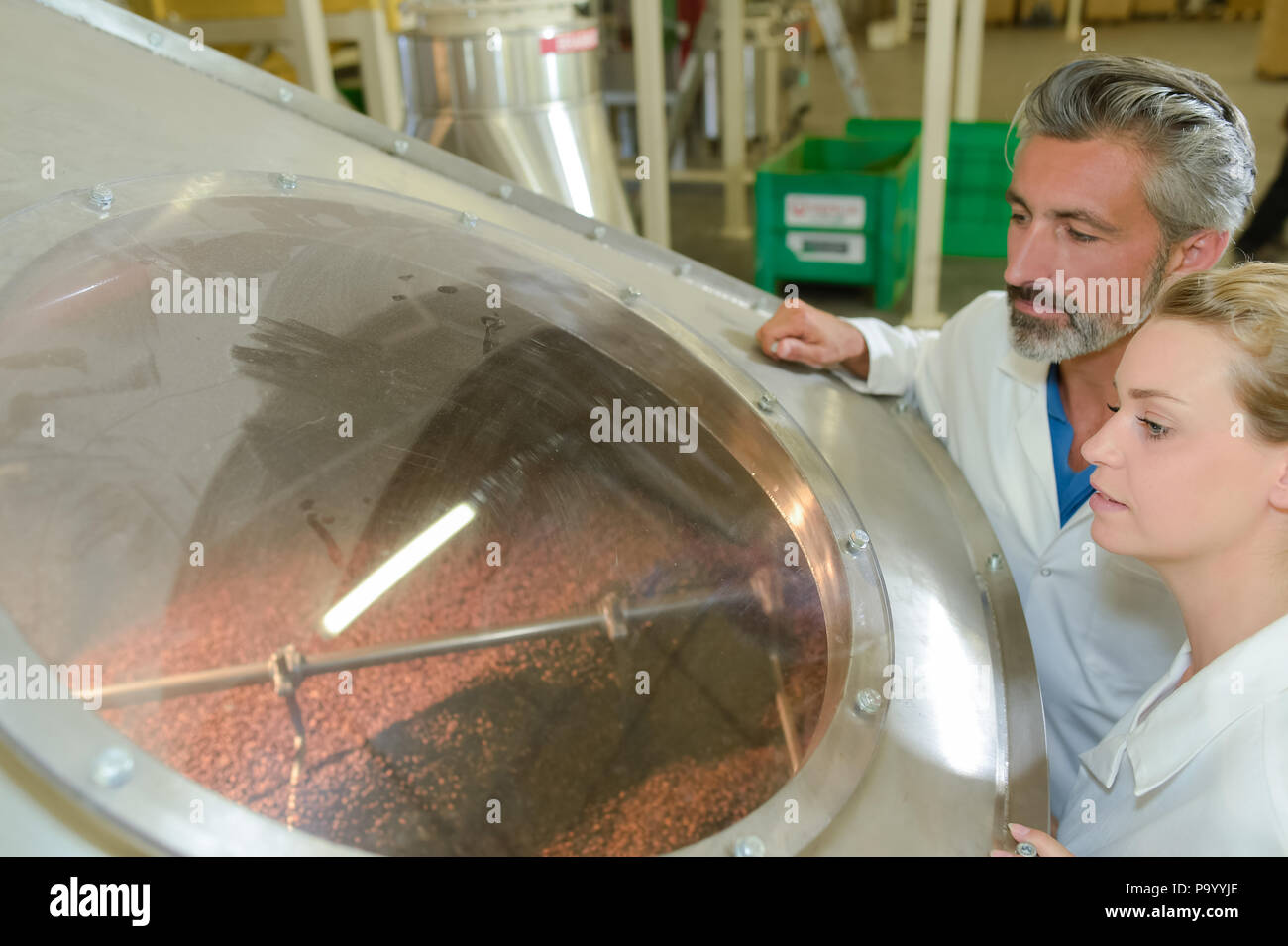 Man and woman looking into vat Stock Photo - Alamy