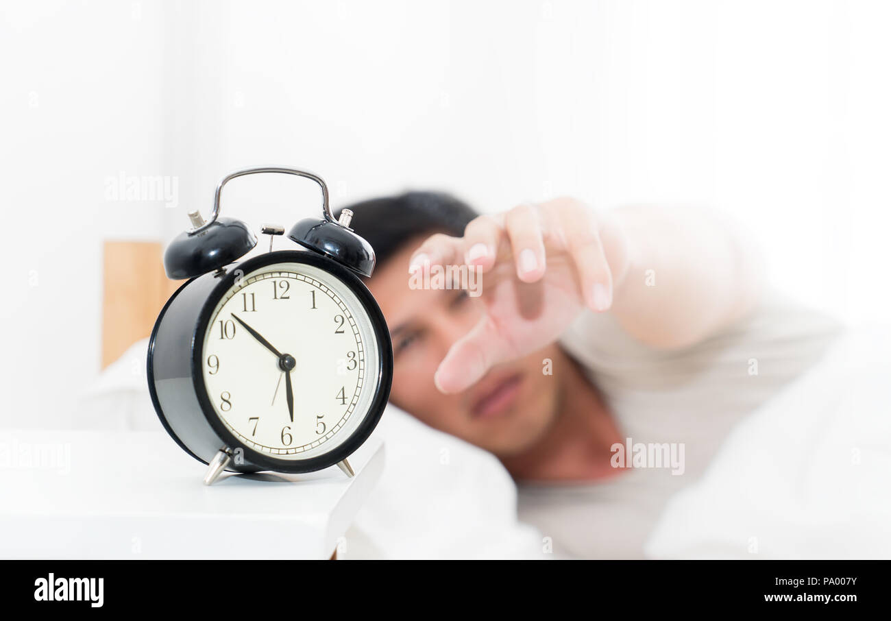 Man's hand is reaching out to alarm clock waking up in early morning ...