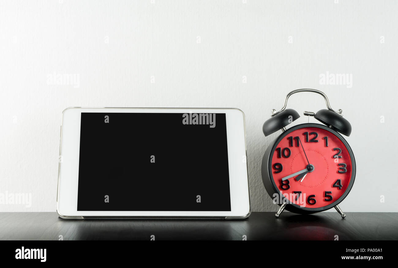 Alarm clock with Blank Tablet screen on office table Stock Photo - Alamy