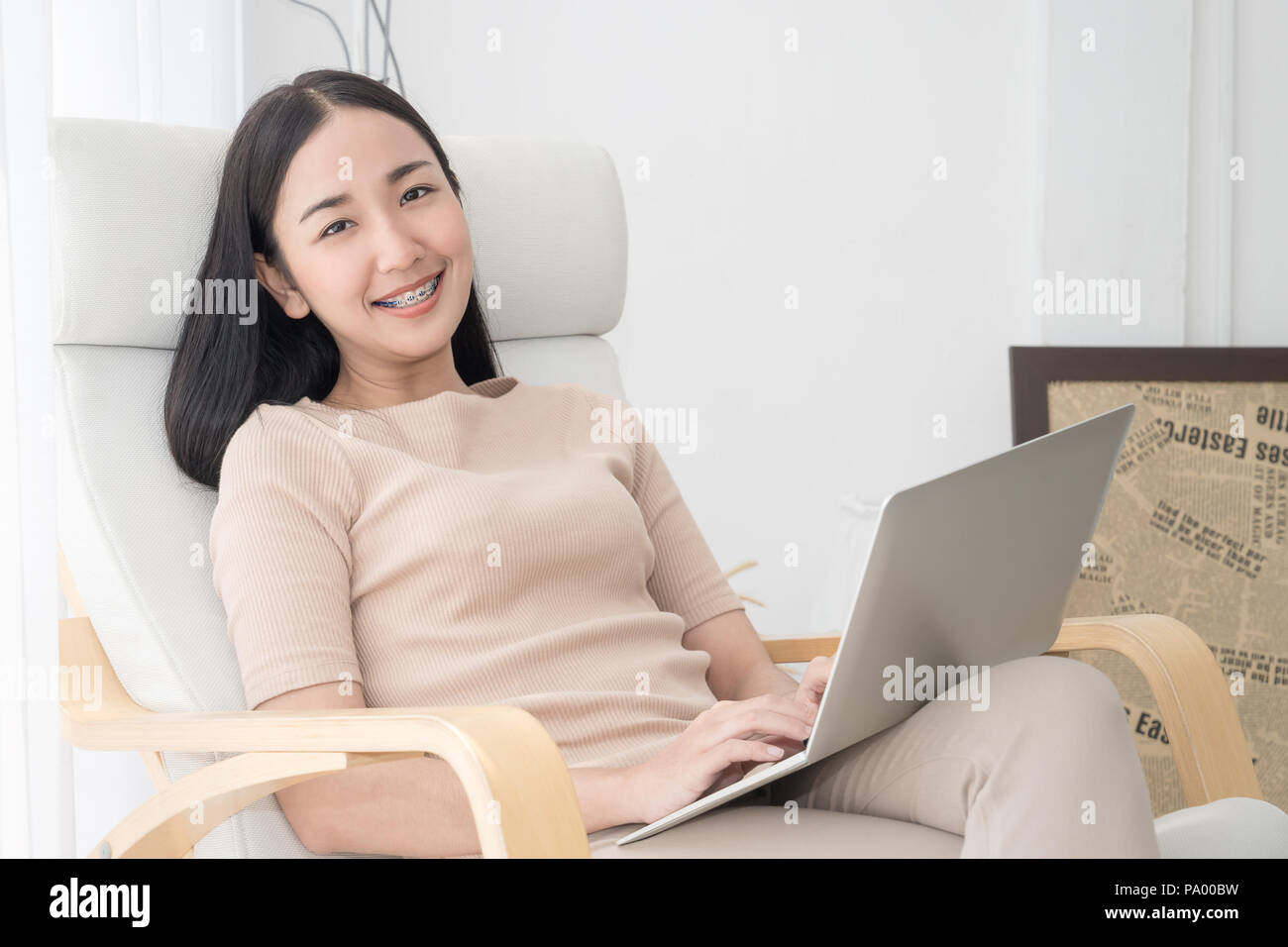 Happy Asian house wife using laptop computer on sofa Stock Photo - Alamy