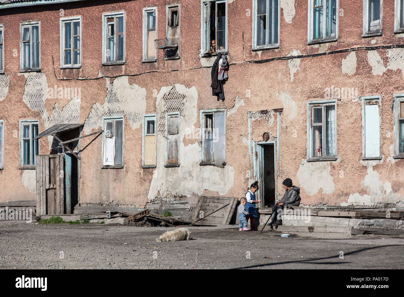 Locals in front of a run down housing block in Lorino, Chukotka, Russia ...