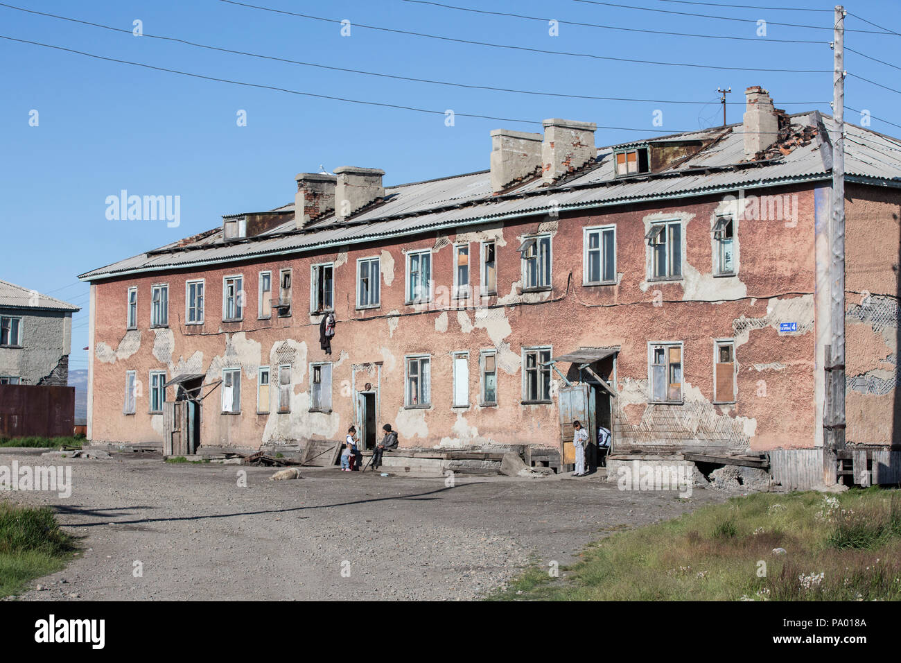 Locals in front of a run down housing block in Lorino, Chukotka, Russia ...